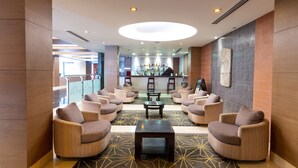 Um hall de hotel com área de bar, disposição de assentos e carpete estampado.