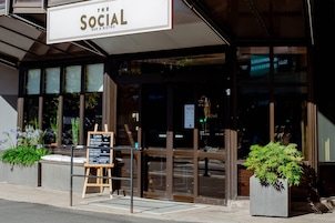 Fachada com uma placa indicando 'The Social Bar & Bistro' e um quadro de menu do lado de fora.
