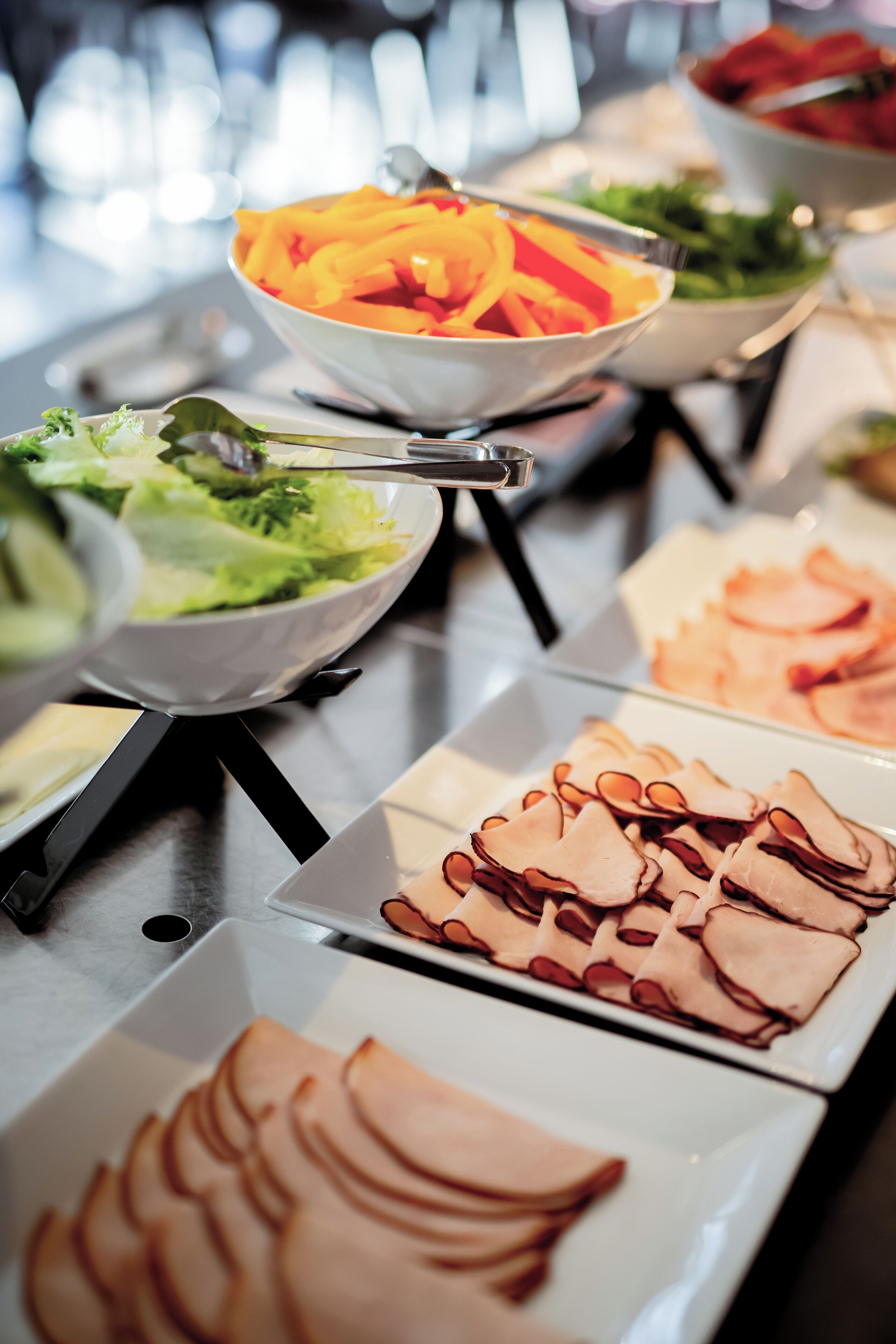Buffet com diversos alimentos, incluindo carnes fatiadas, vegetais e saladas.