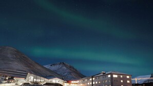 Um hotel com vários edifícios, paisagem coberta de neve e uma montanha ao fundo.