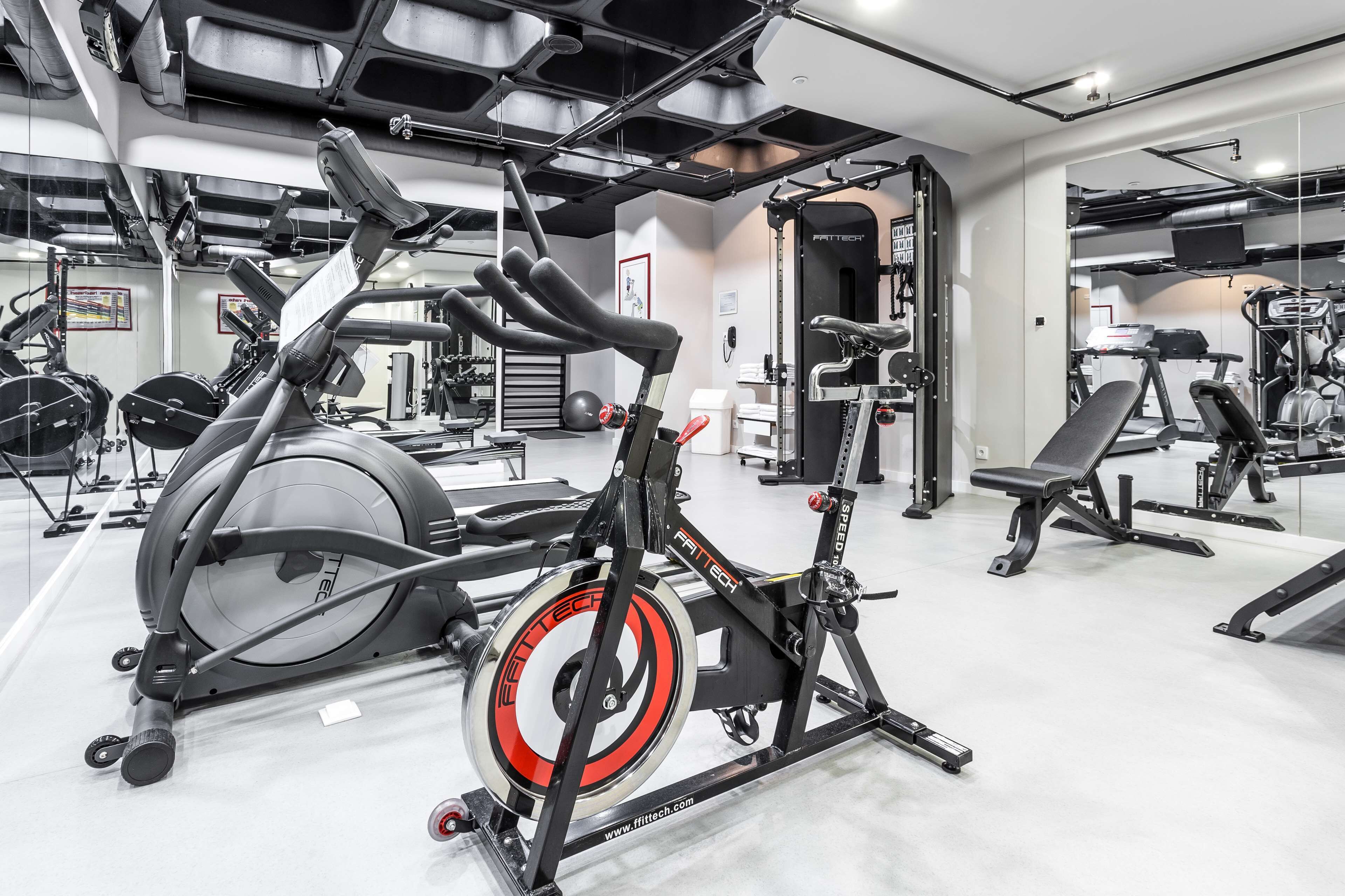 Academia moderna com diversos equipamentos de ginástica, incluindo bicicleta ergométrica e aparelhos de musculação.