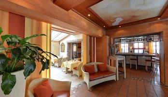 Um quarto espaçoso com área de jantar, bar e canto de estar com uma planta grande.