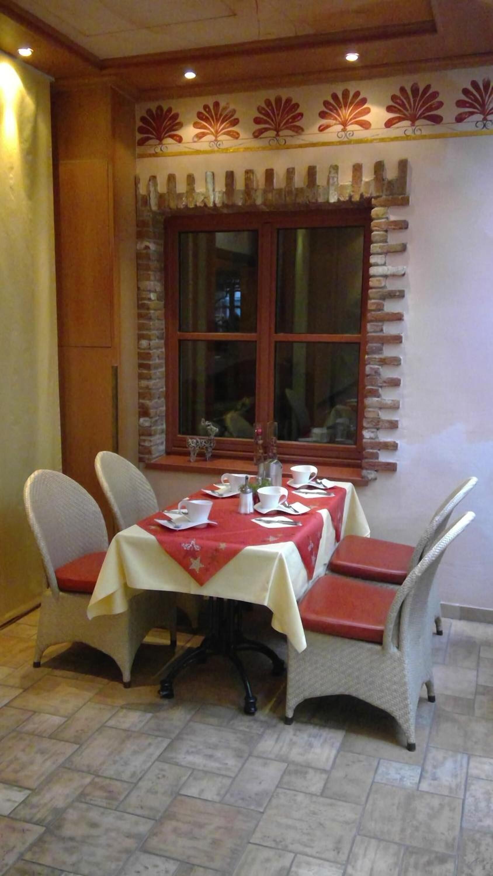 Uma área de refeições com uma mesa posta para quatro pessoas, rodeada de cadeiras.