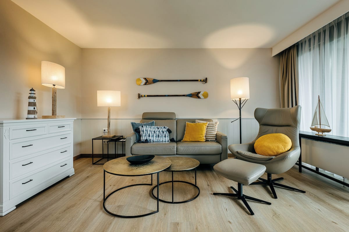 Uma sala de estar moderna com um sofá, poltronas, uma mesa de centro e uma mesa lateral com luminárias.