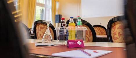 Sala de conferências com tela de projeção, um decantador de vidro e um suporte para bebidas.