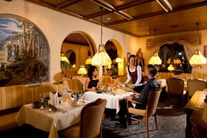 Restaurante com cabines de madeira, toalhas de mesa brancas e lustres.