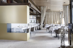 Restaurante moderno com um salão de refeições amplo, mesas e cadeiras brancas.