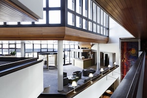 Um lobby espaçoso com pé direito alto, grandes janelas e design moderno.