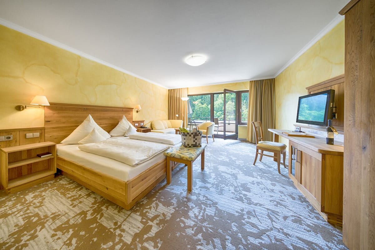 Quarto de hotel com cama grande, escrivaninha, televisão e vista para o exterior.