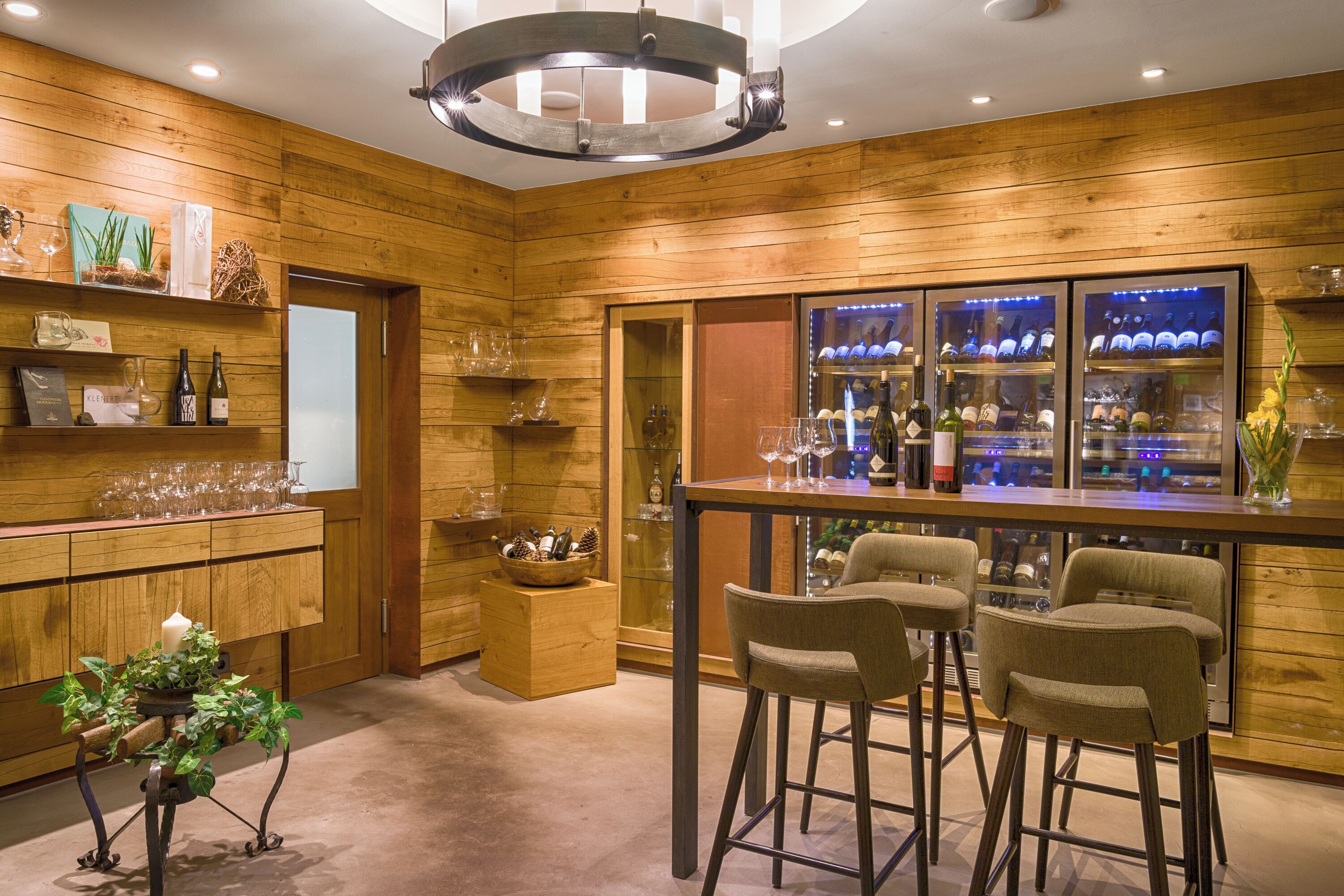 Interior em madeira com área de bar, banquetes e prateleiras com garrafas e copos.
