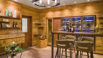 Interior em madeira com área de bar, banquetes e prateleiras com garrafas e copos.