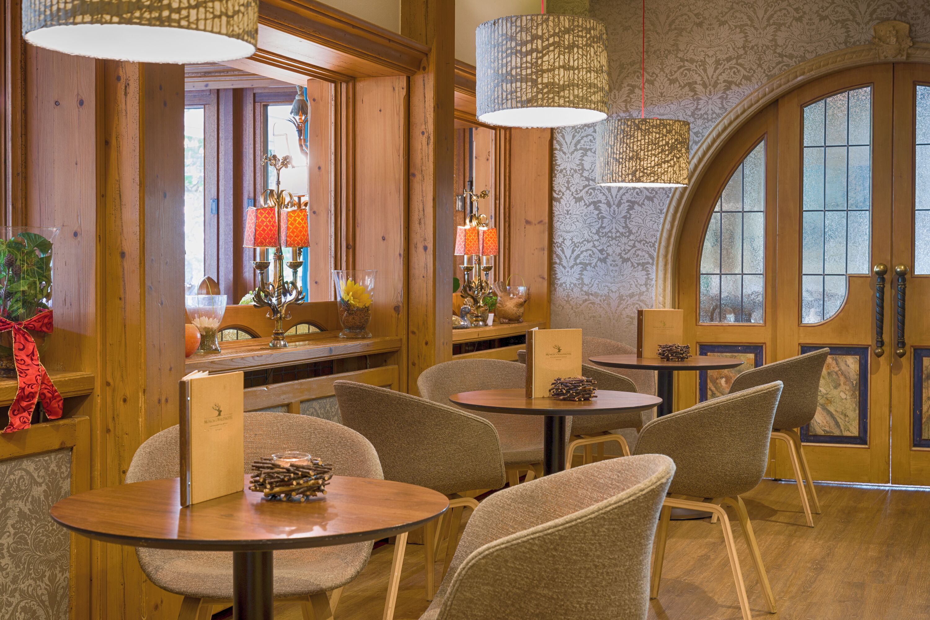 Um restaurante acolhedor com móveis de madeira, iluminação pendente e uma grande porta em arco.