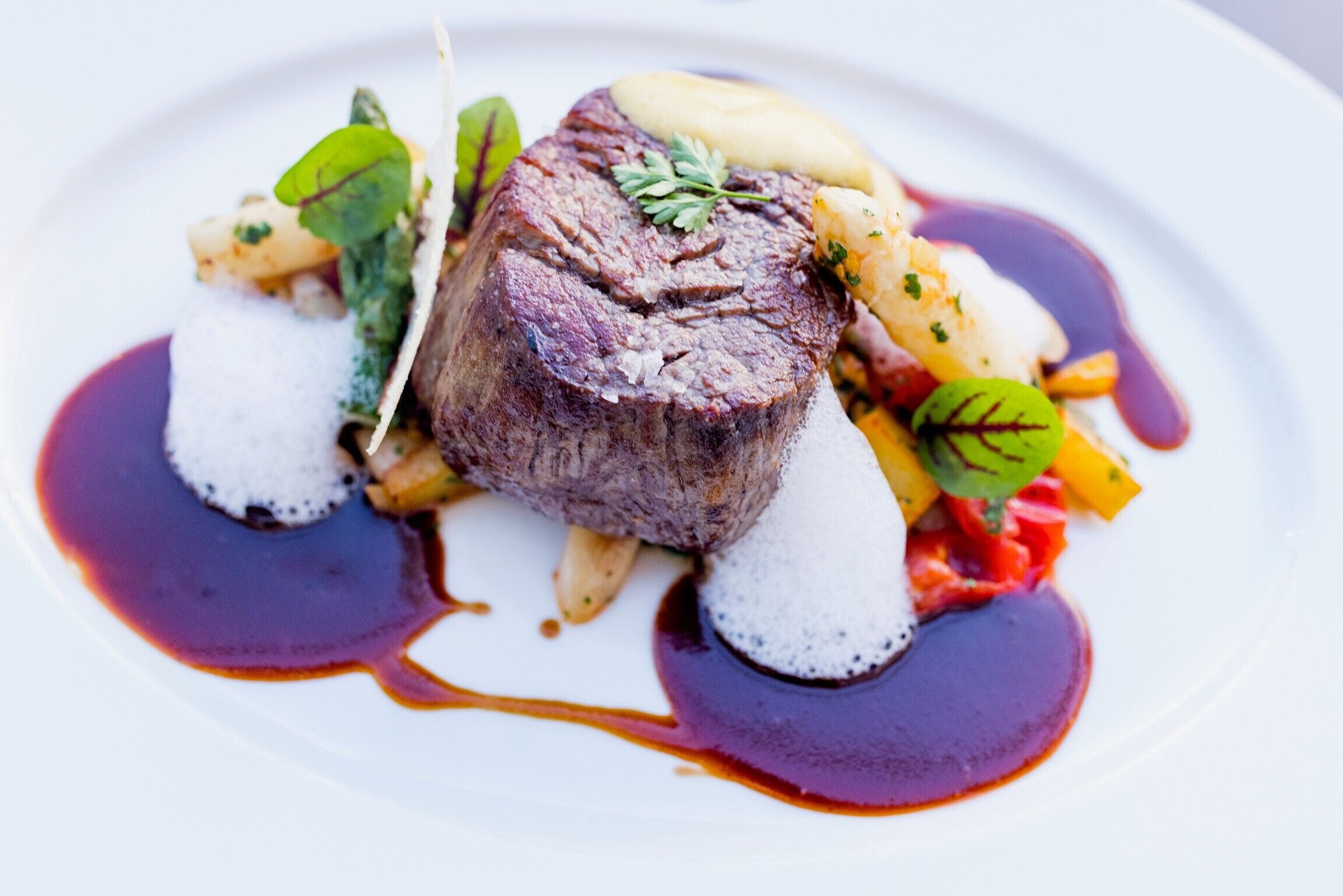 Bife com legumes e molho em um prato.