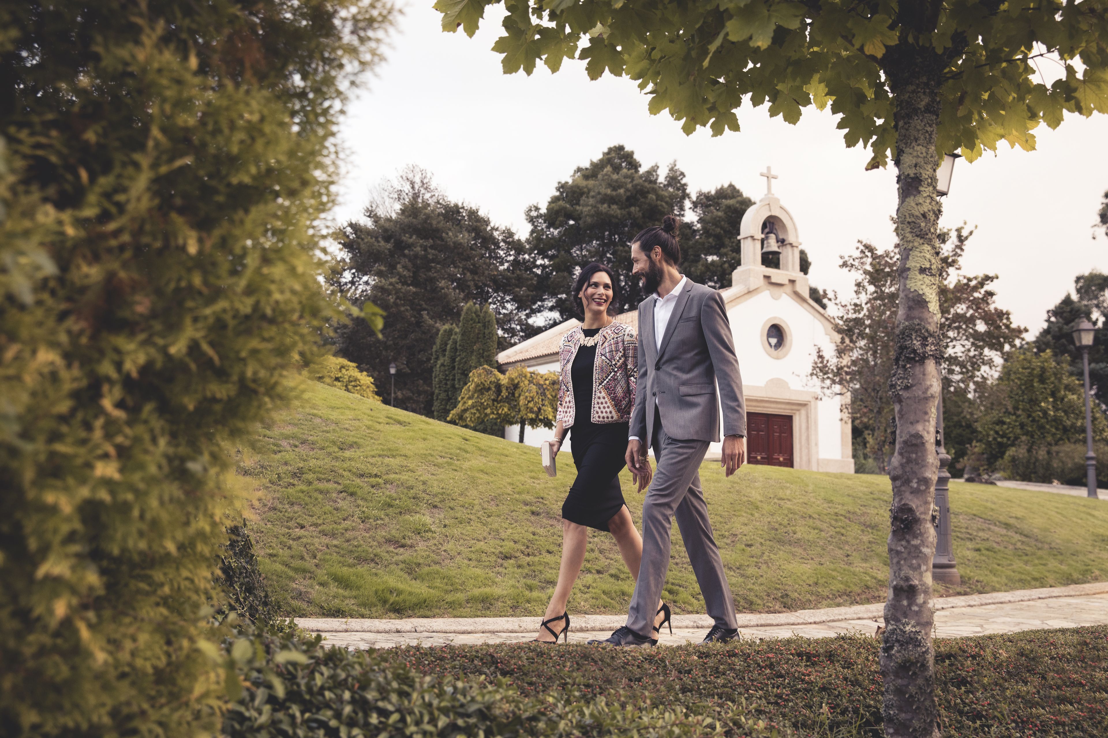 Um casal caminhando por um caminho, com uma igreja ao fundo.