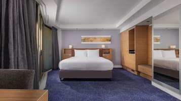 Quarto de hotel com uma cama grande, mesa de cabeceira, guarda-roupa e espelho.