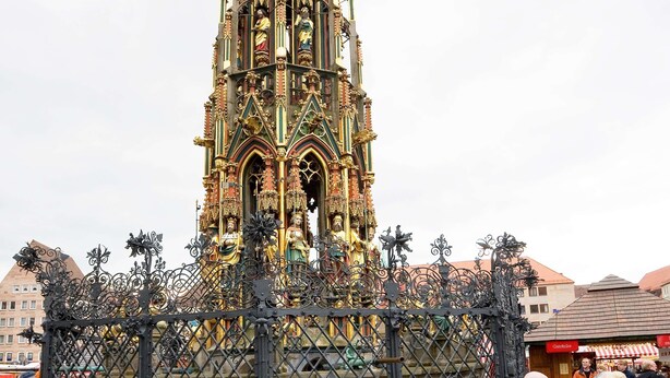 Uma torre histórica com detalhes arquitetônicos elaborados e uma cerca decorativa na frente.
