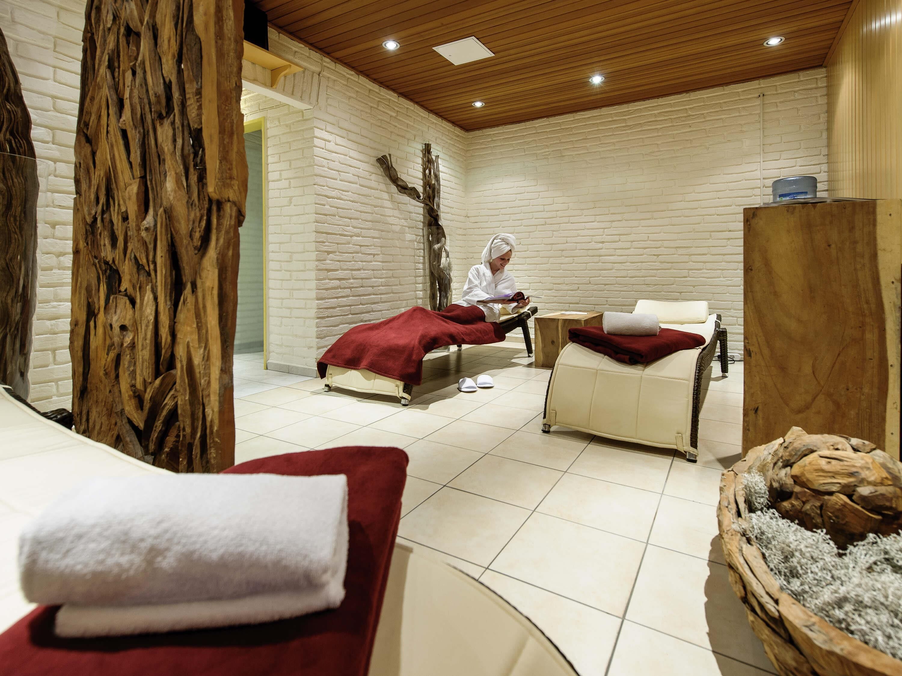 Uma sala de spa com duas camas, decoração em madeira e uma parede de tijolos brancos.