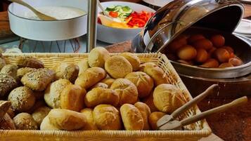 Uma mesa de buffet com diversos pães, um caldeirão de sopa e uma cesta de ovos.