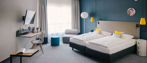 Quarto de hotel moderno com uma cama grande, escrivaninha, cadeira e televisão.