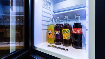 Uma geladeira com várias garrafas de bebidas, incluindo Fanta, FuzeTea e Coca-Cola.