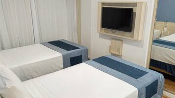 Quarto de hotel com duas camas, televisão fixada na parede e um espelho refletindo o ambiente.