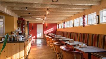 Restaurante com vigas de madeira, área de bar e cabines listradas.