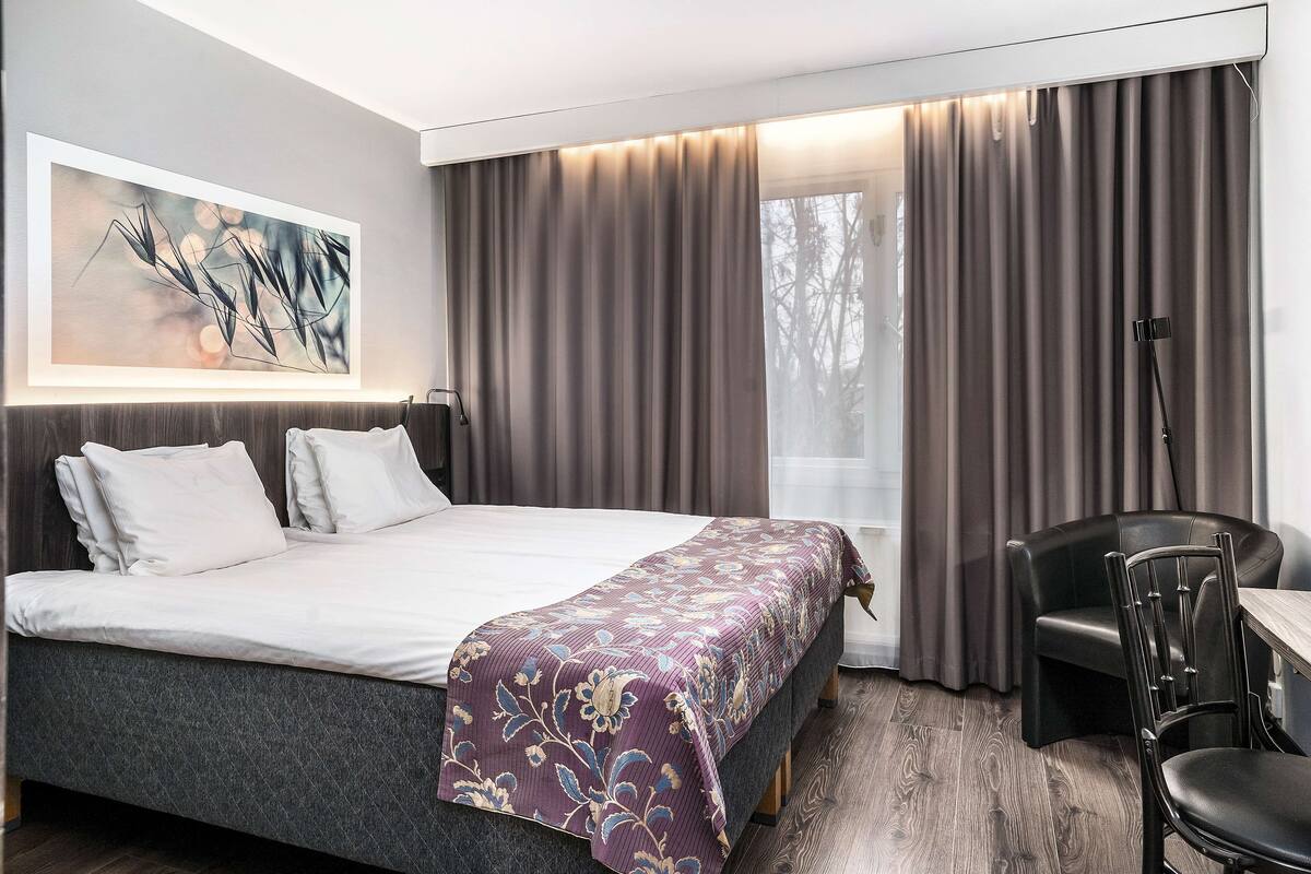 Quarto de hotel moderno com uma cama grande, uma escrivaninha e uma cadeira.