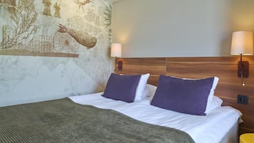 Quarto de hotel com cama, duas luminárias fixadas na parede, cabeceira de madeira e um mural decorativo.