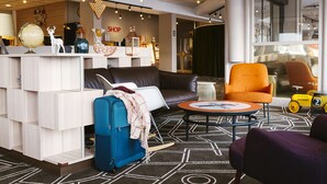 Uma área de estar moderna com um sofá, poltronas, uma mesa de centro e um suporte para malas.