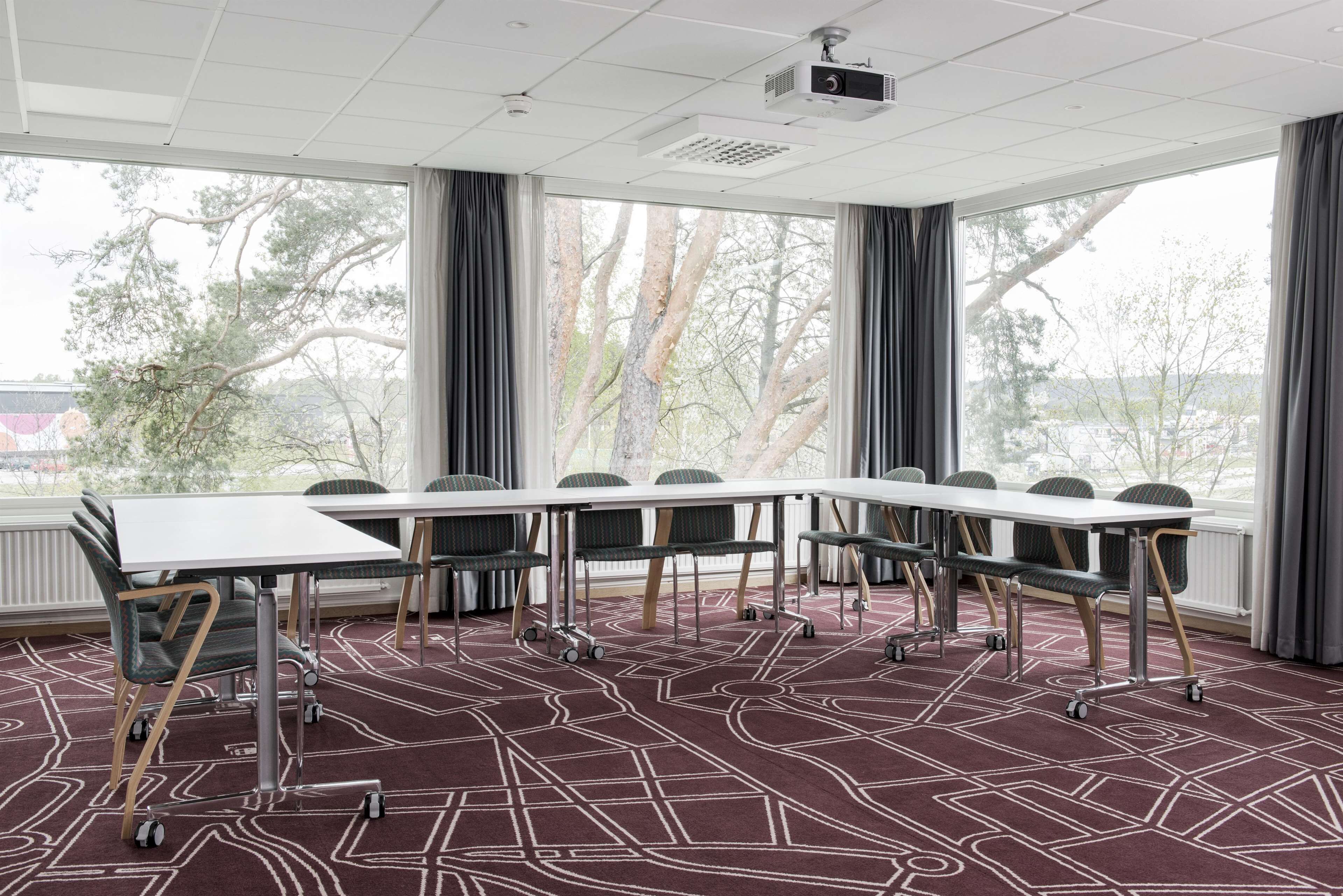 Uma sala de conferências com uma mesa grande, cadeiras e um projetor.