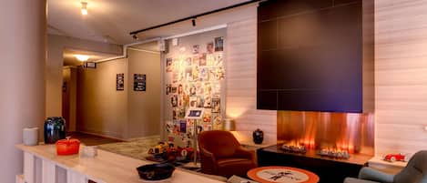 Uma sala de estar moderna com uma mesa de centro de madeira, lareira e uma parede decorada com fotos.