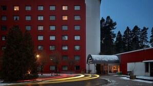 Um edifício vermelho com uma placa 'Scandic', uma entrada coberta e terreno coberto de neve.
