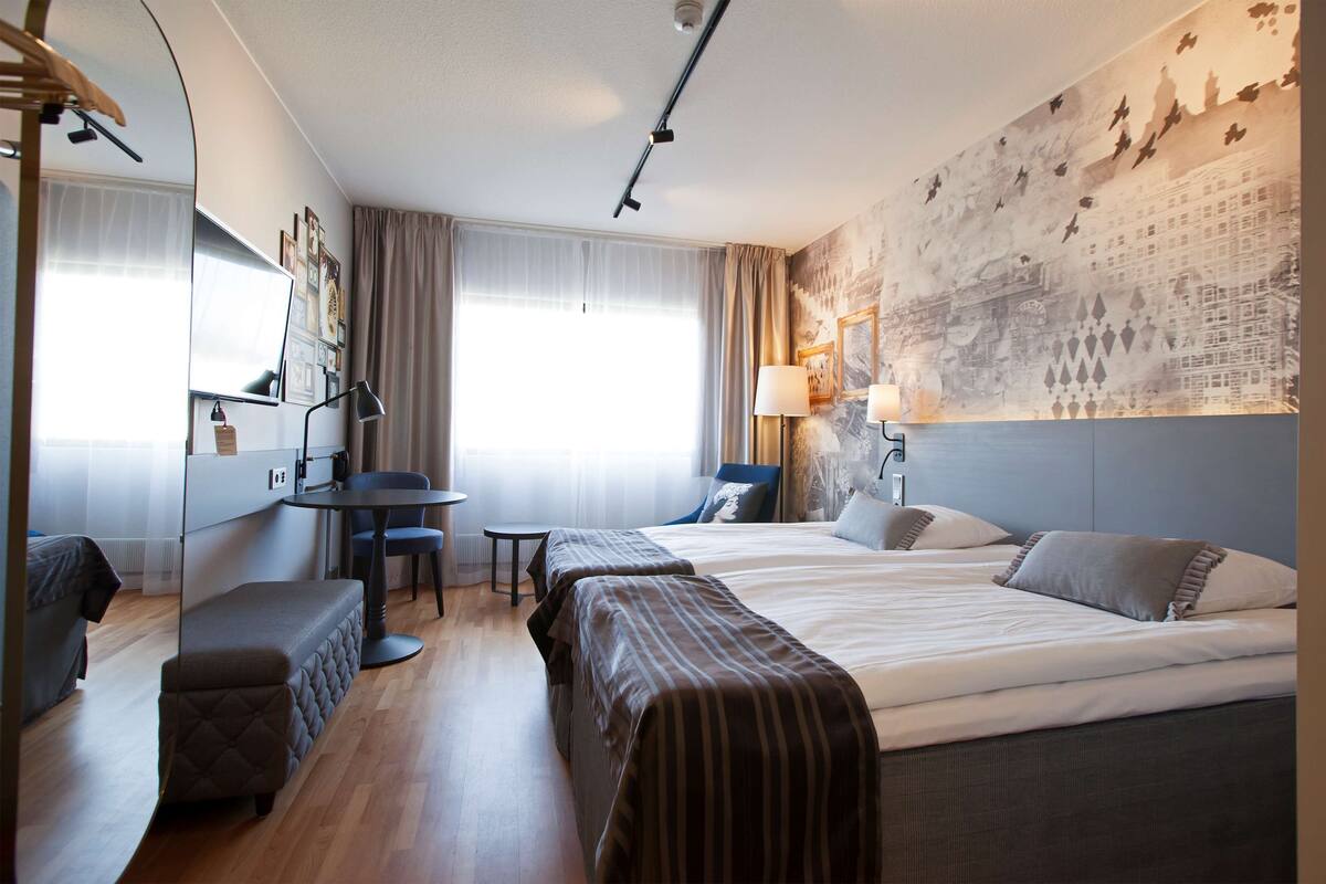 Quarto de hotel com uma cama grande, uma mesa, uma cadeira e uma pequena mesa.
