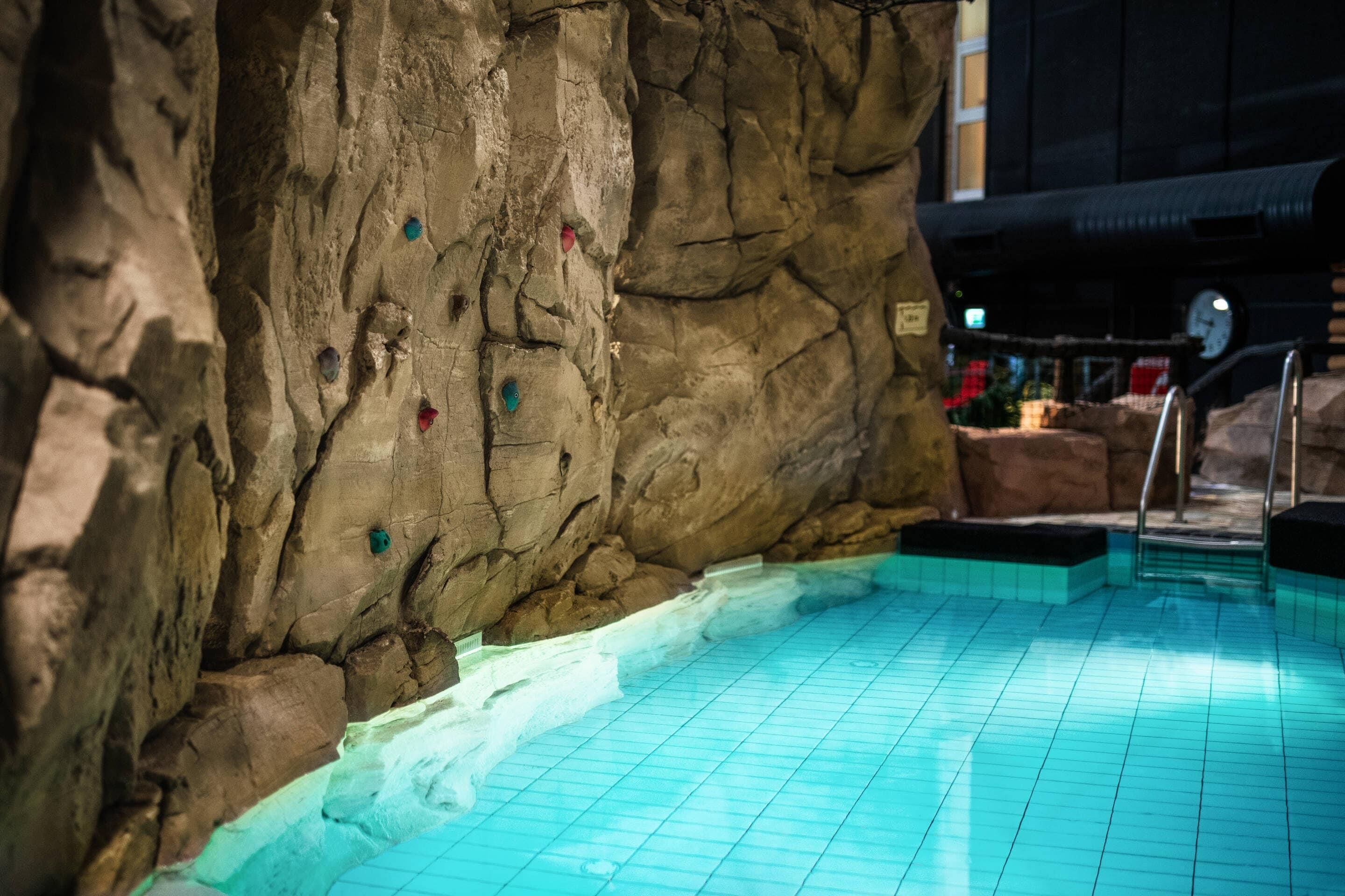 Uma piscina com uma parede de pedra e um relógio.