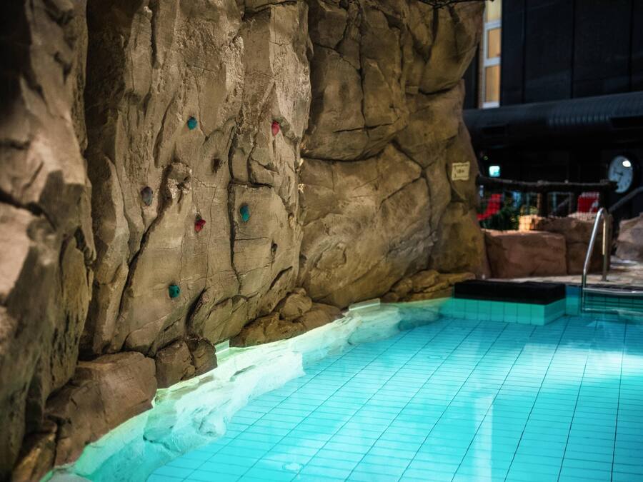Uma piscina com uma parede de pedra e um relógio.