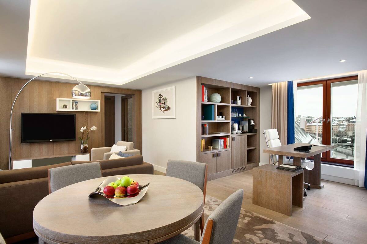 Uma sala de estar moderna com uma mesa de jantar redonda, um sofá, uma televisão e uma estante de livros.