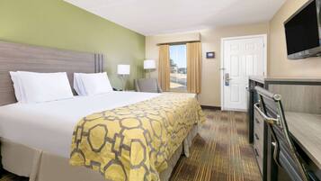 Quarto de hotel com uma cama grande, duas luminárias de cabeceira, uma TV fixada na parede e uma porta que dá para o exterior.