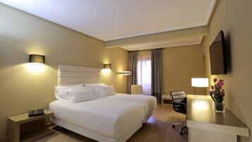 Quarto de hotel moderno com uma cama grande, mesas de cabeceira, escrivaninha, cadeira e televisão de tela plana na parede.