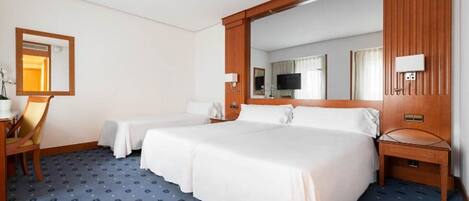 Quarto de hotel com duas camas, uma escrivaninha, uma cadeira, um espelho e uma televisão.