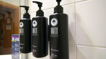 Três embalagens pretas de chá de eucalipto Roots para aromaterapia sobre uma parede com azulejos brancos.