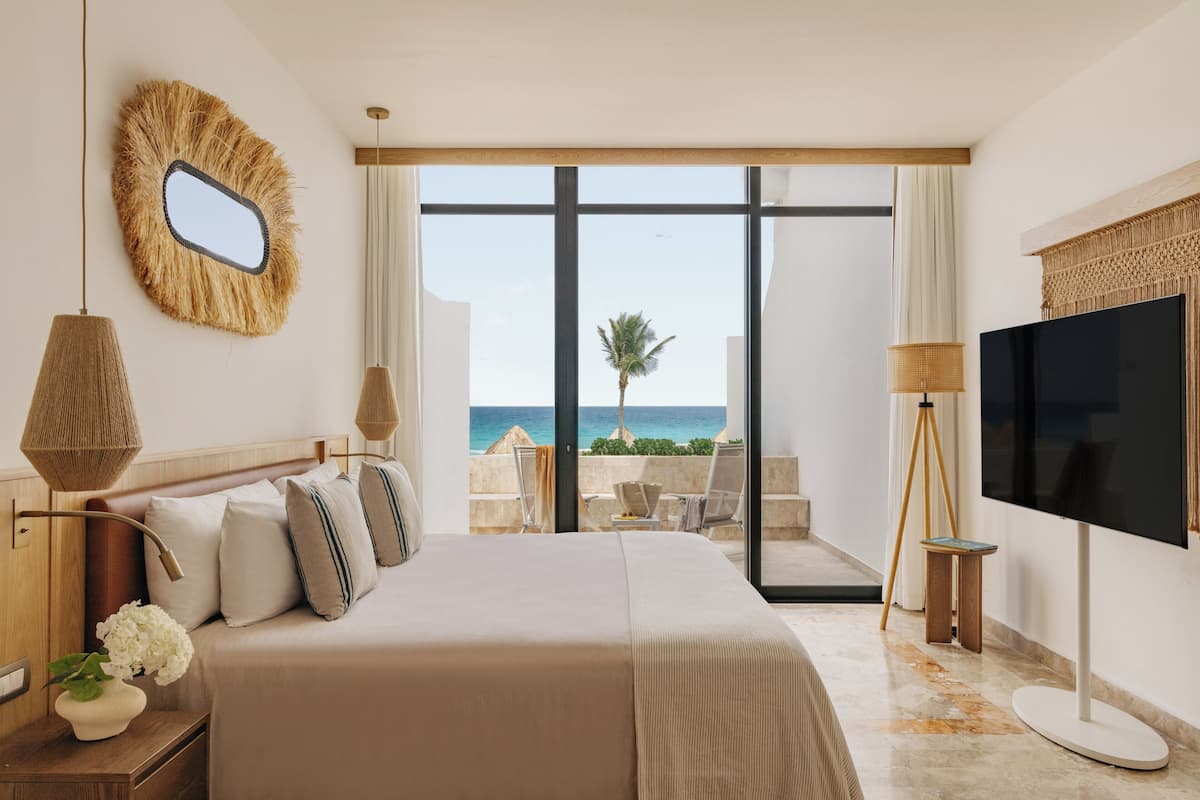 Quarto com cama, TV e vista para o mar.