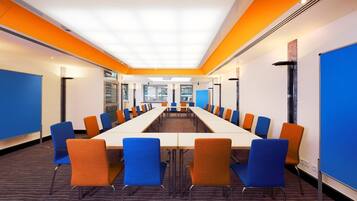 Uma sala de conferências com uma mesa comprida e cadeiras, janelas amplas e um design moderno no teto.