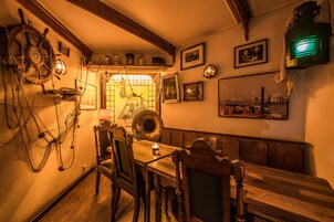 Uma sala de jantar com mobiliário de madeira, um adorno de leme e arte decorativa com tema náutico.