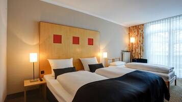 Quarto de hotel com duas camas, cabeceira de madeira, luminárias de cabeceira e uma janela grande com cortinas.