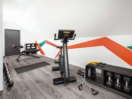Uma academia com bicicleta ergométrica, esteira e aparelhos de musculação.