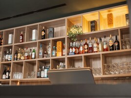 Uma área de bar com prateleiras repletas de garrafas de bebidas e copos.