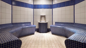 Uma sala de sauna com paredes e bancos revestidos em azulejos.