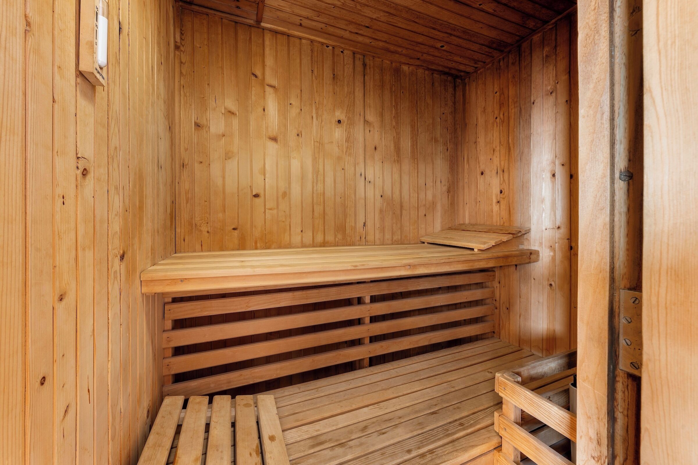 Uma sauna de madeira com bancos e um assento de banco.
