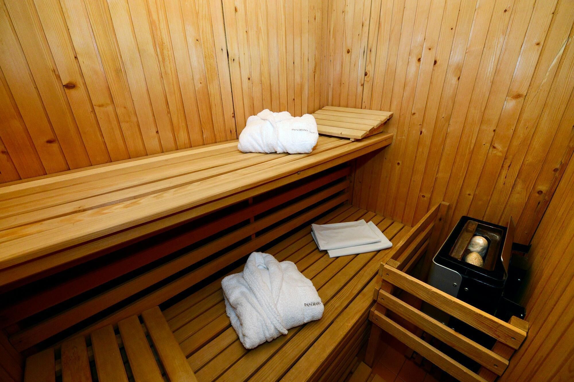 Uma sauna de madeira com bancos, toalhas e aquecedor.