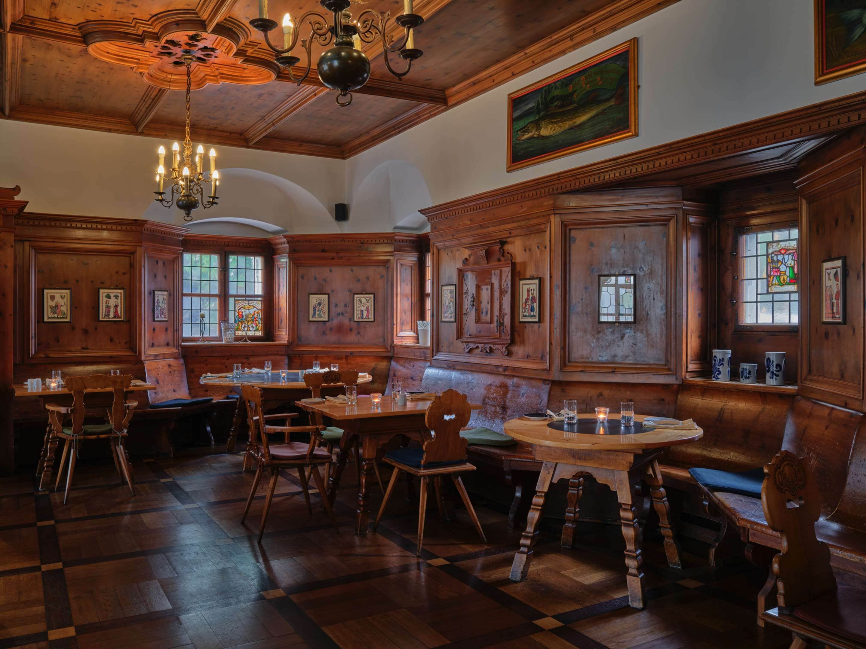 Uma sala de jantar tradicional com painéis de madeira, lustres e obras de arte nas paredes.